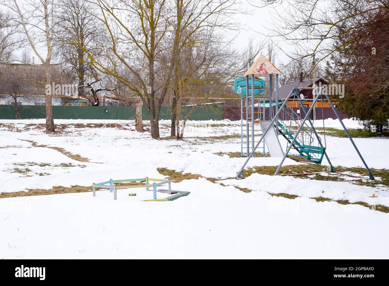Children's playground in winter under snow. Swing, carousel and slide ...