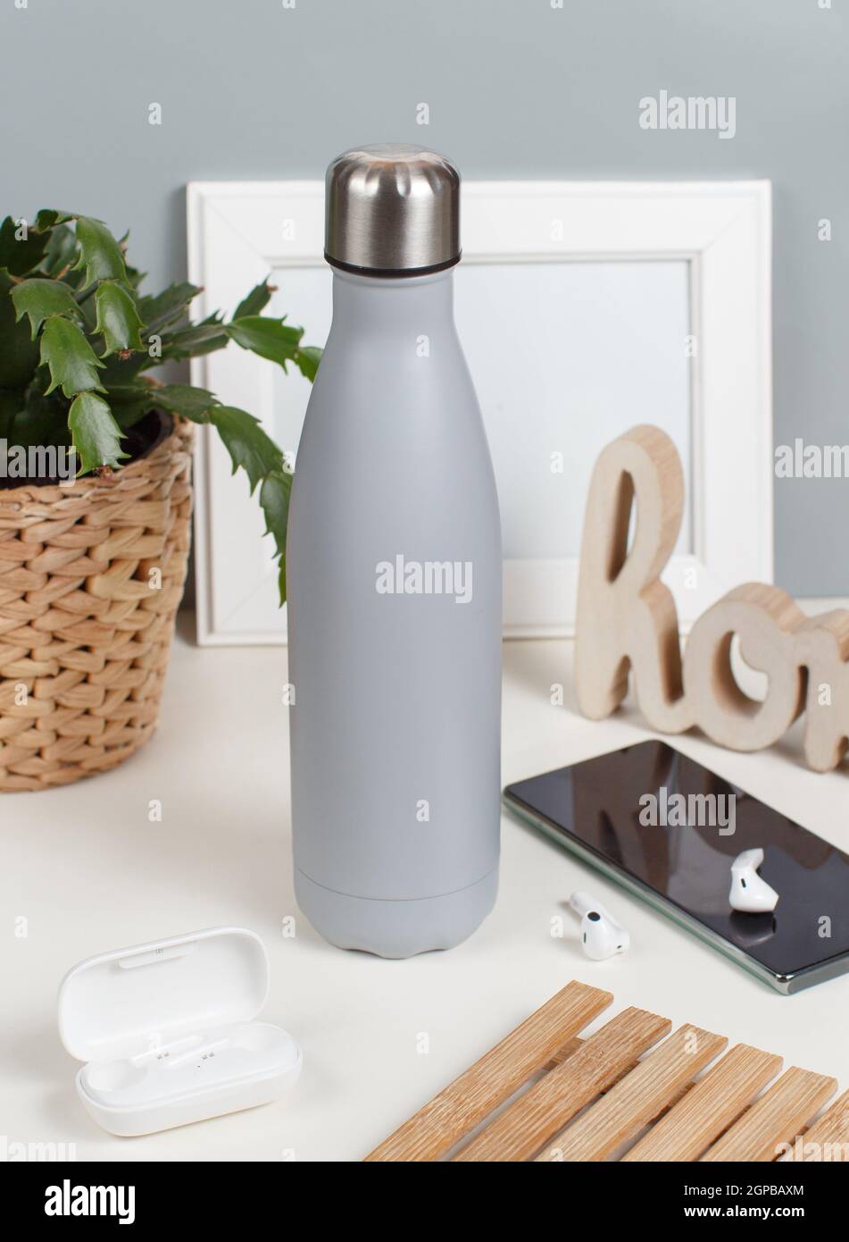 Grey insulated bottle on white desk surrounded by modern gadgets and ...