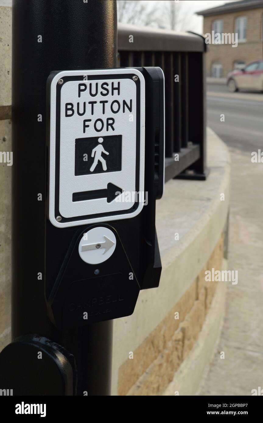 A closeup view of a new modern crosswalk push button at a busy street ...