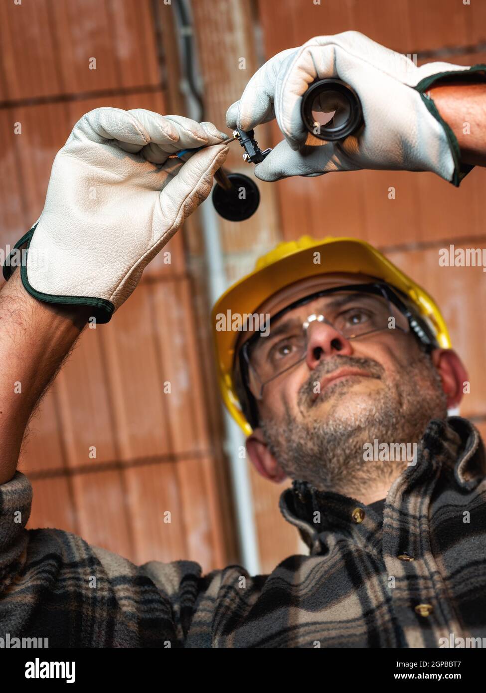 Electrician worker at work replaces the lamp holder in a residential ...