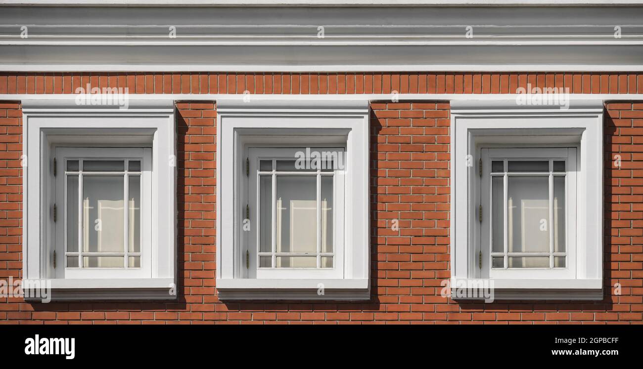 Three white windows on red brick wall of residential building Stock ...