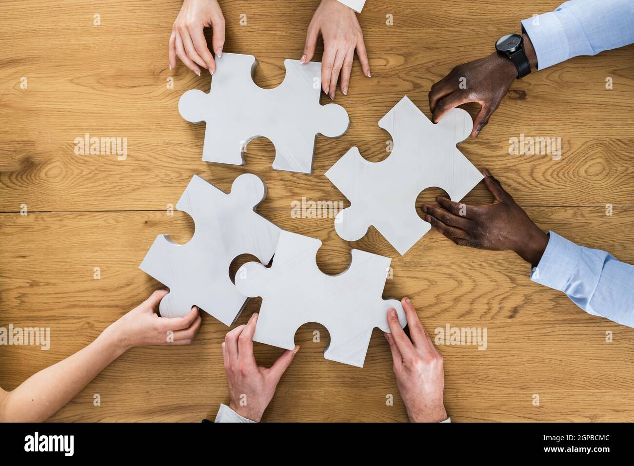 Teamwork Meeting Hands Solving Jigsaw Puzzle At Desk Stock Photo - Alamy