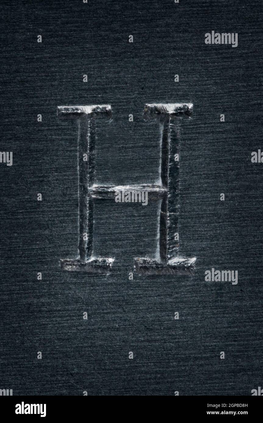 Detailed view of the letter H embossed into a gray and sanded steel ...