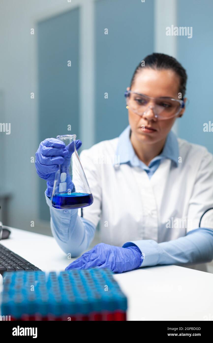 Scientist woman doctor analyzing glassware with blue solution ...