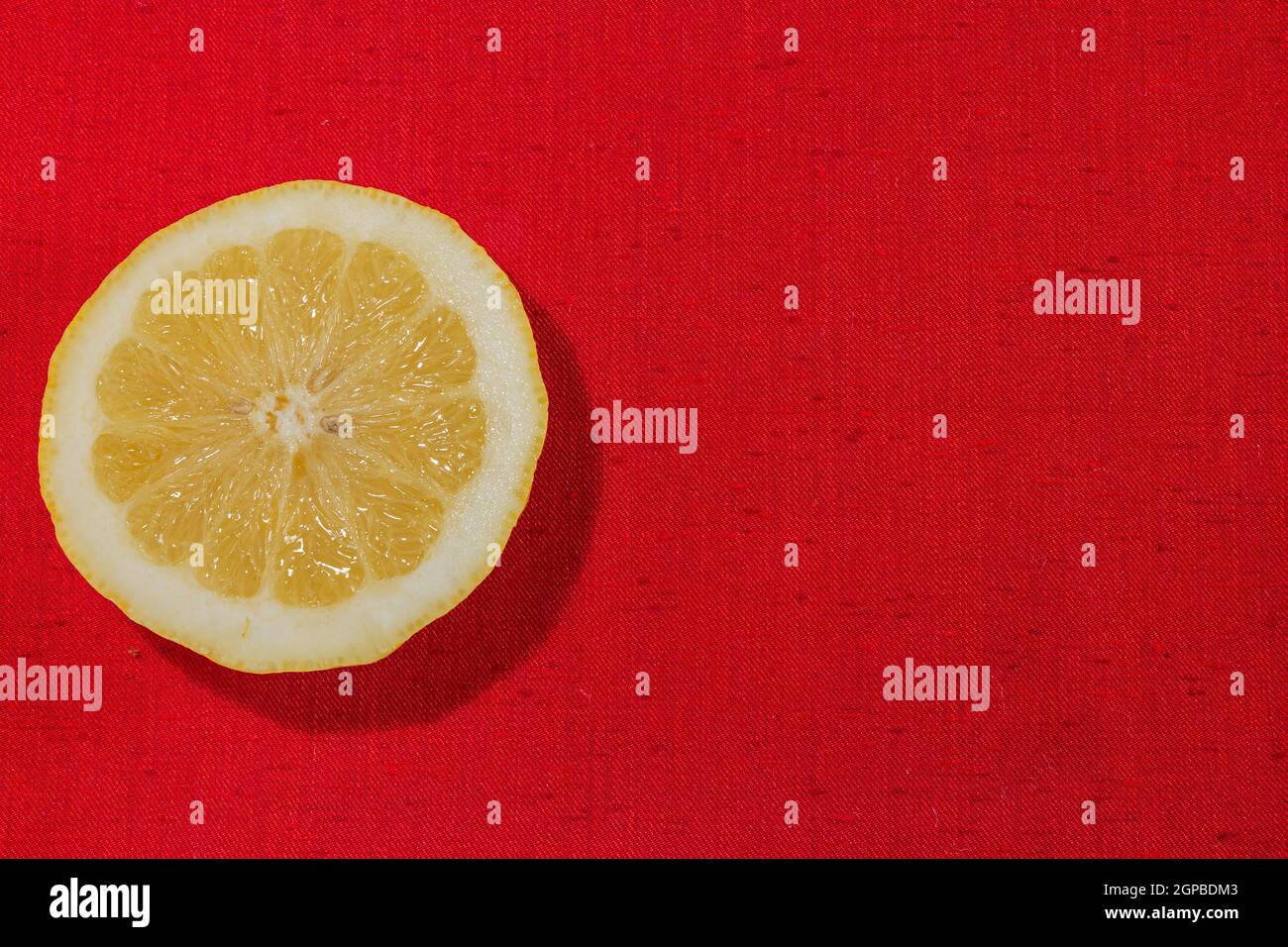 Detail of fresh sliced lemon on a rustic canvas fabric texture in red ...