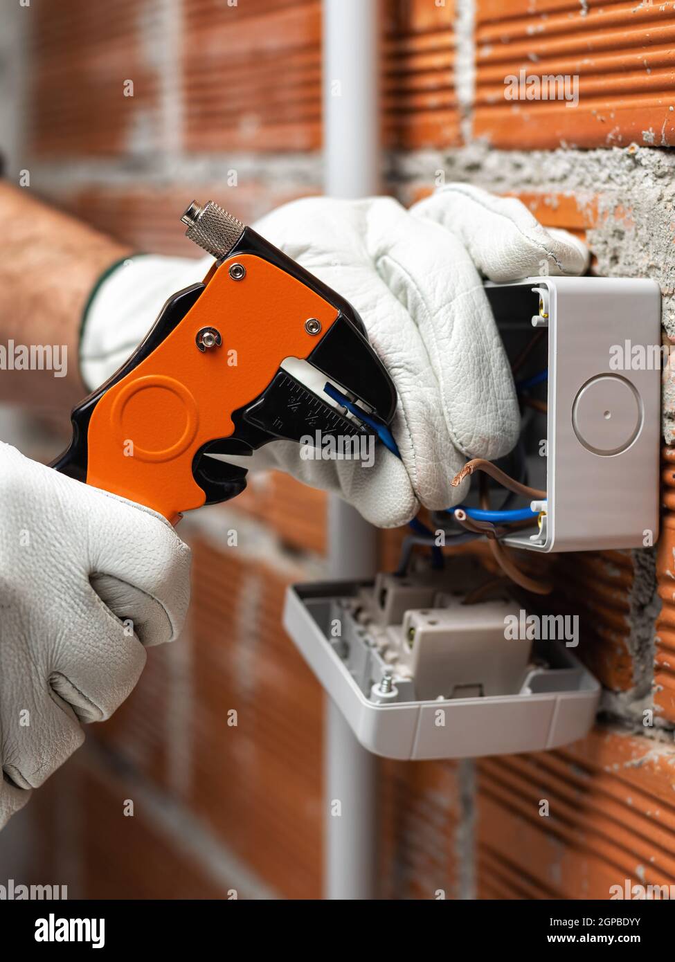 Electrician worker at work with wire stripper prepares electrical ...