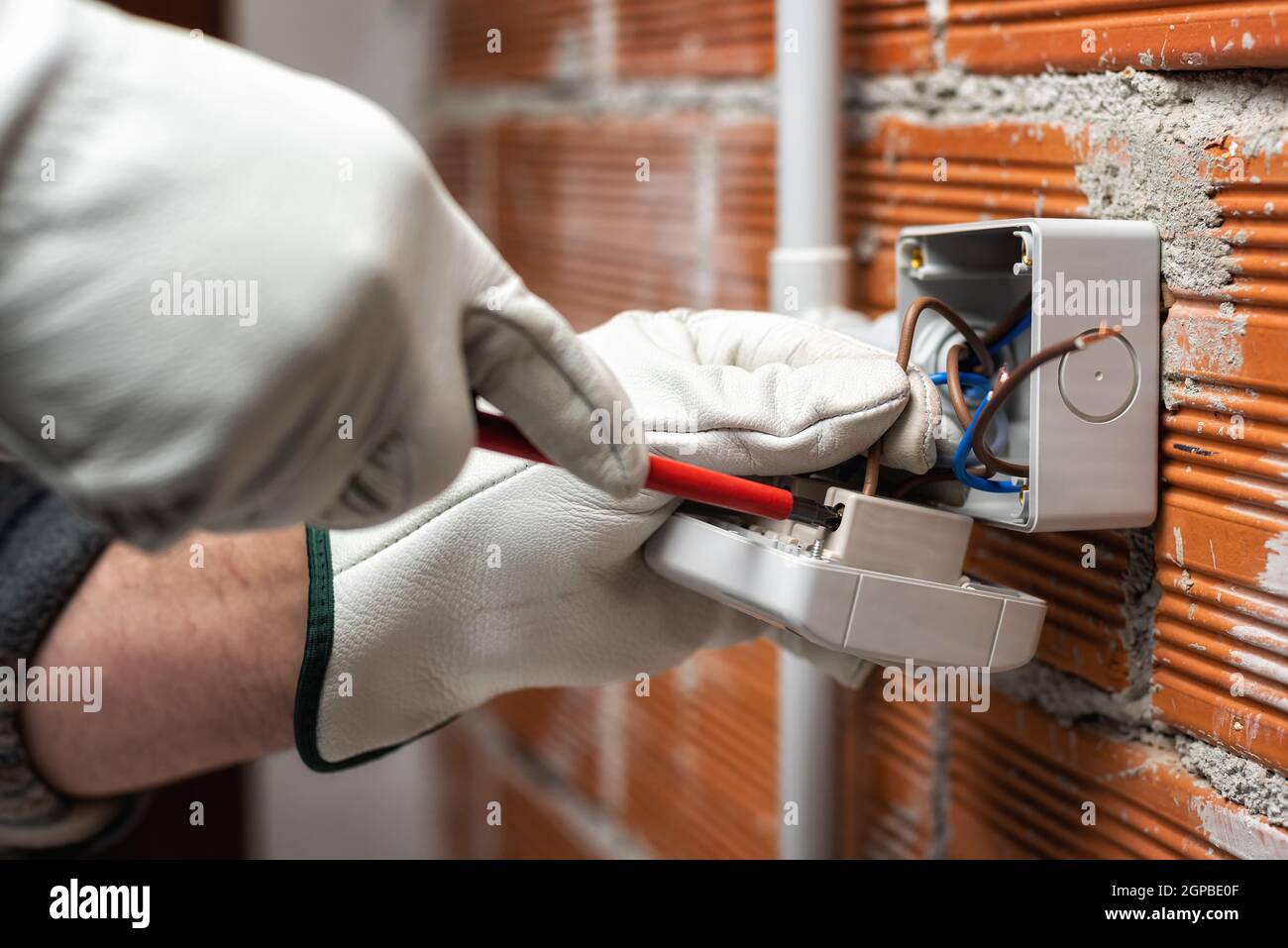 Electrician worker at work with screwdriver fixes the cable in the ...