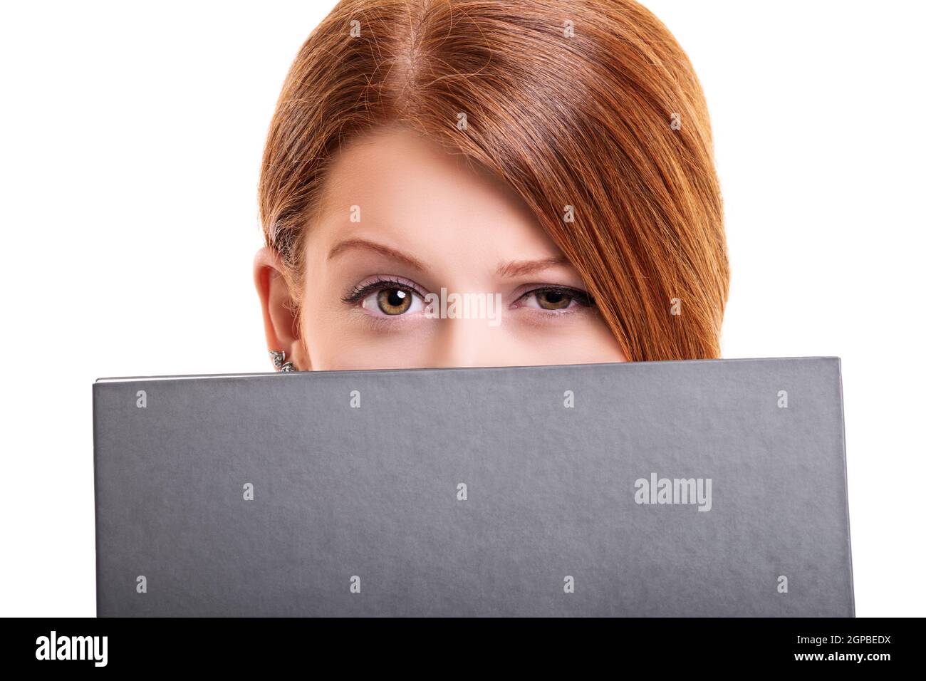 Close up portrait of a young woman hiding her face behind a book, with ...