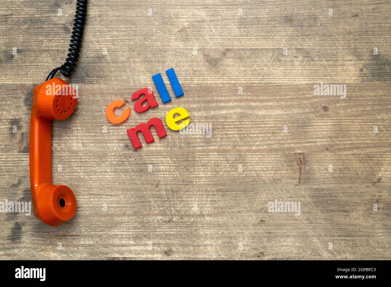 Retro phone handle hanging down on a cord near words Call me. Urgent ...