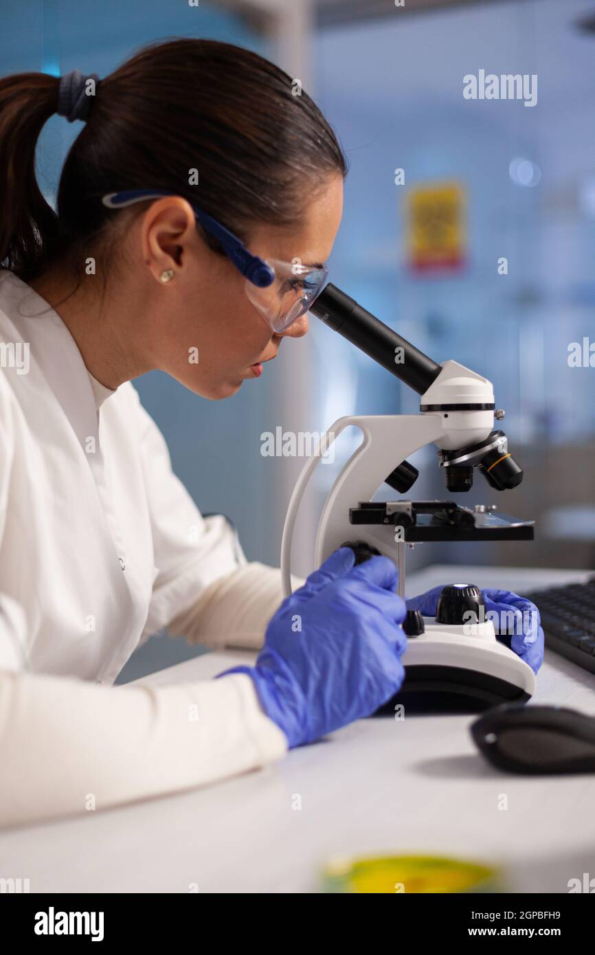 Microbiology specialist testing dna sample on microscope in science ...