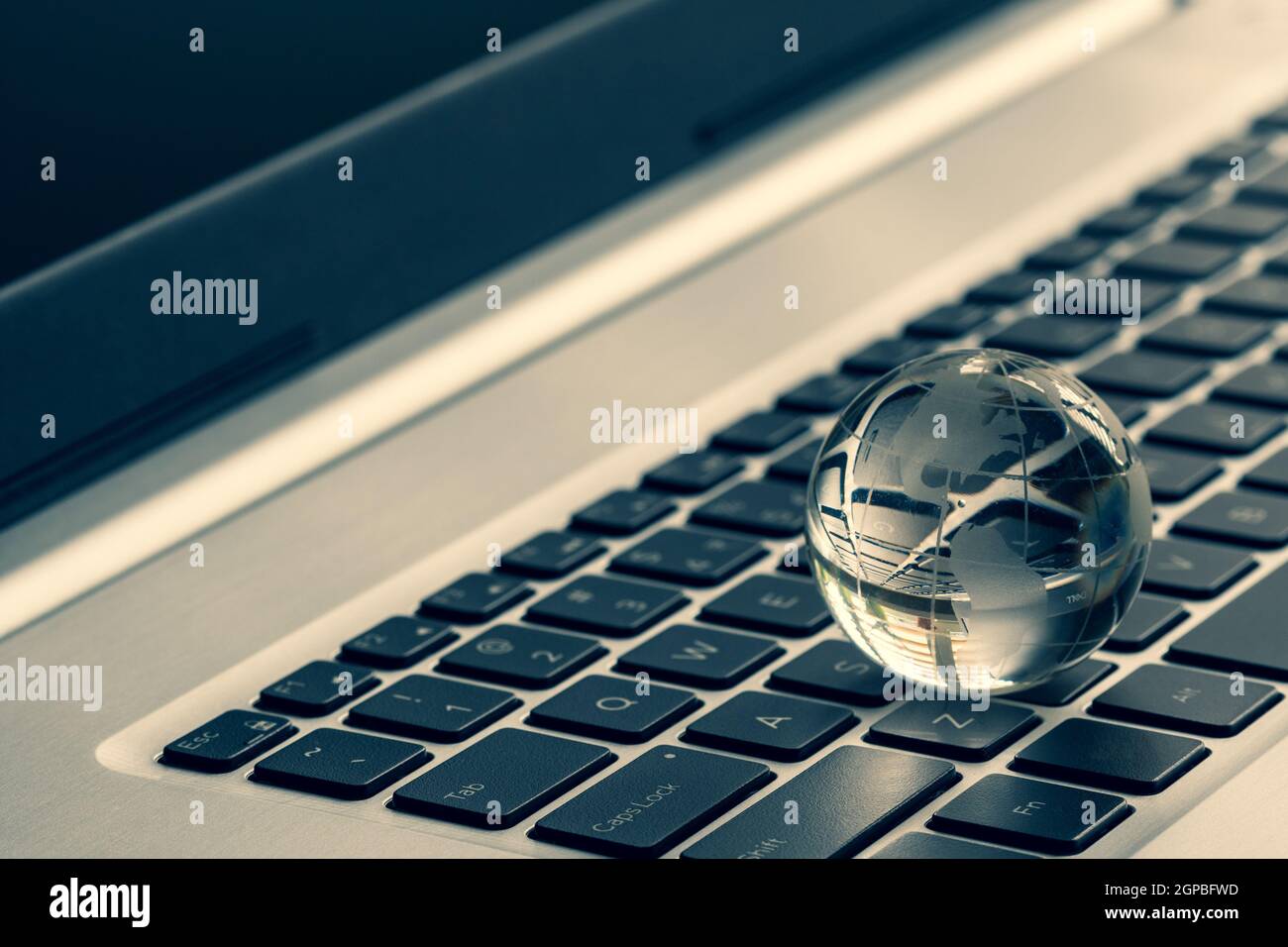 Global computer business concept with small globe on laptop keyboard ...