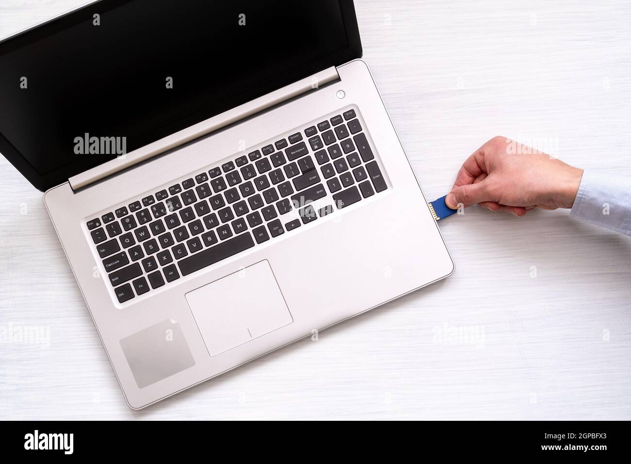 Hand inserting SD memory card into laptop slot Stock Photo - Alamy