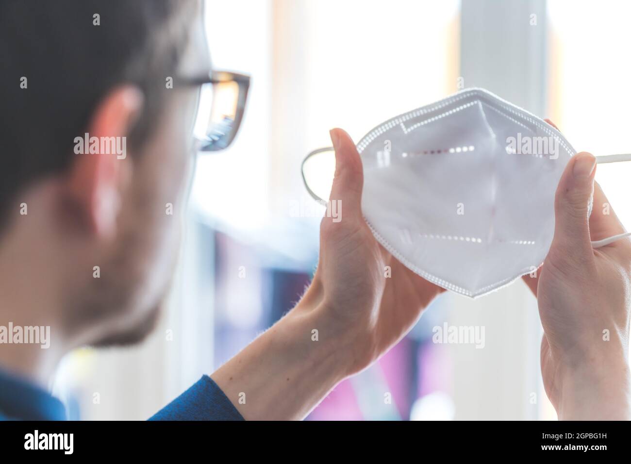 Young man in pulling on ffp2 anti corona mask Stock Photo - Alamy