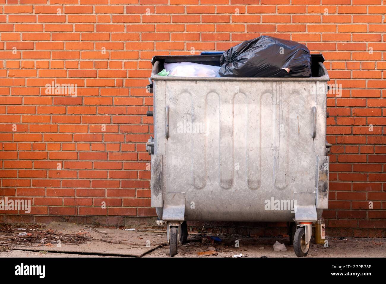 Trashcan full of garbage, standing over brick wall Stock Photo - Alamy