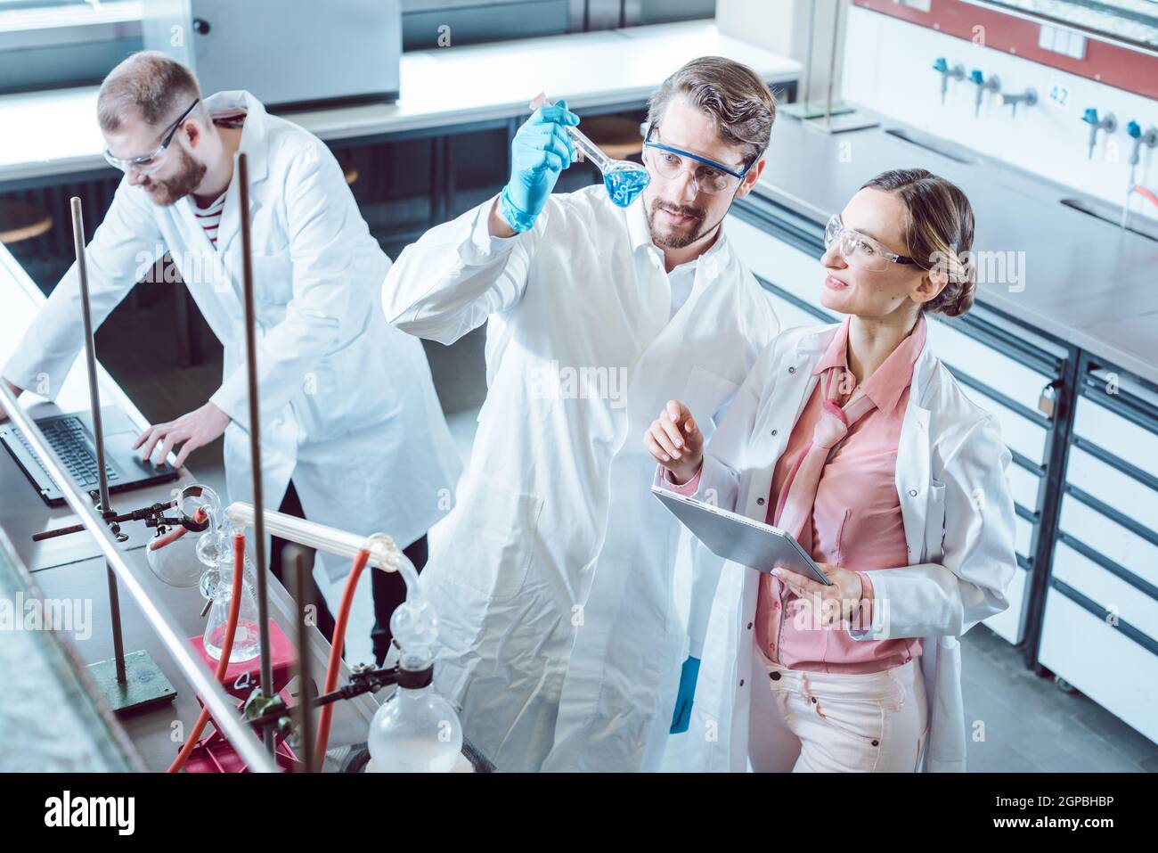 Team of scientists during experiment in the lab looking at test glass ...