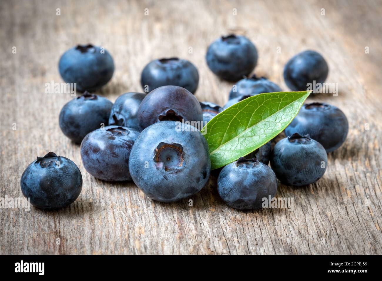 Fresh whortleberry with a green leaf on old wood background Stock Photo ...
