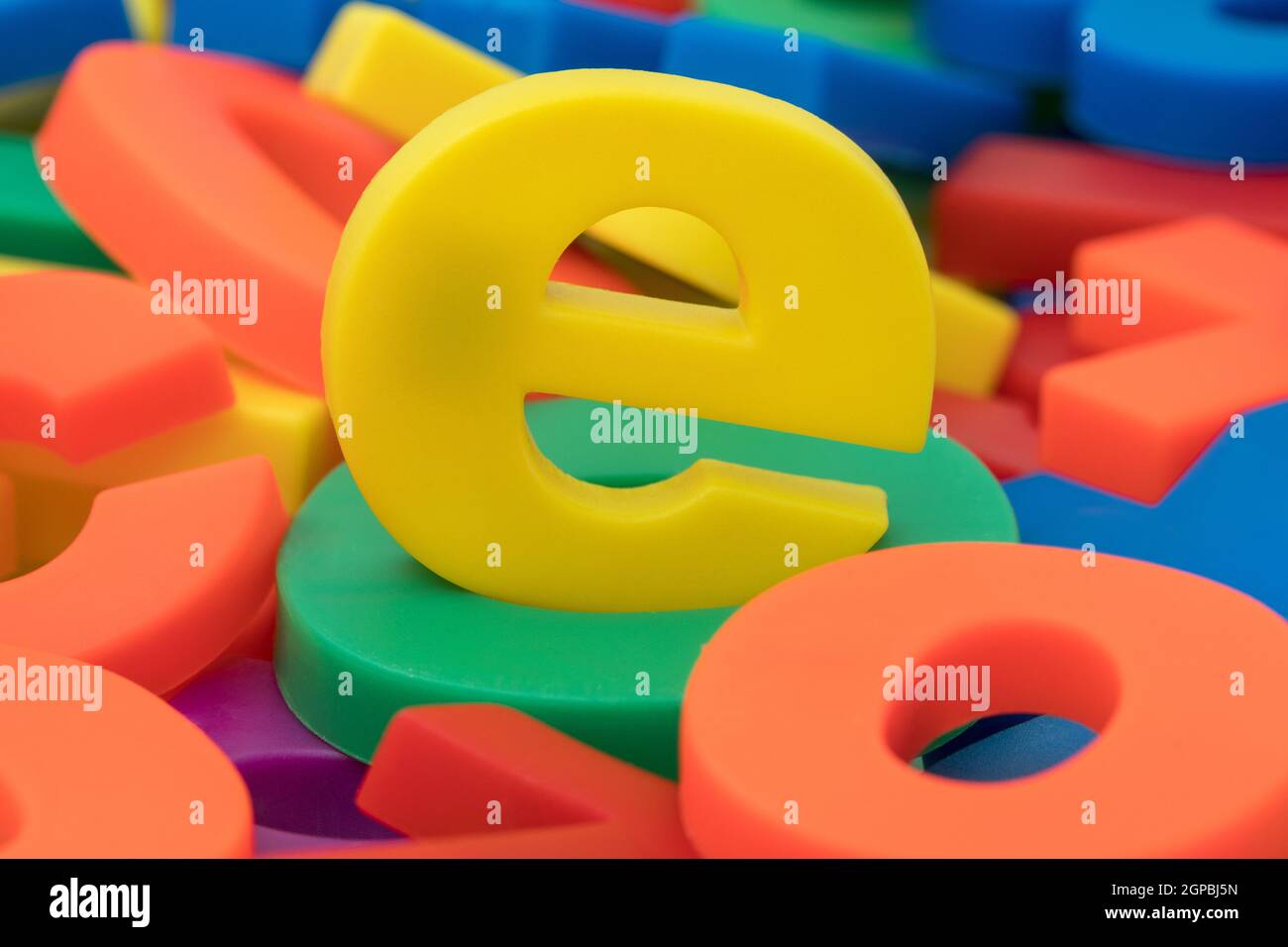 Yellow letter "e" on the pile of colorful plastic letters and numbers ...