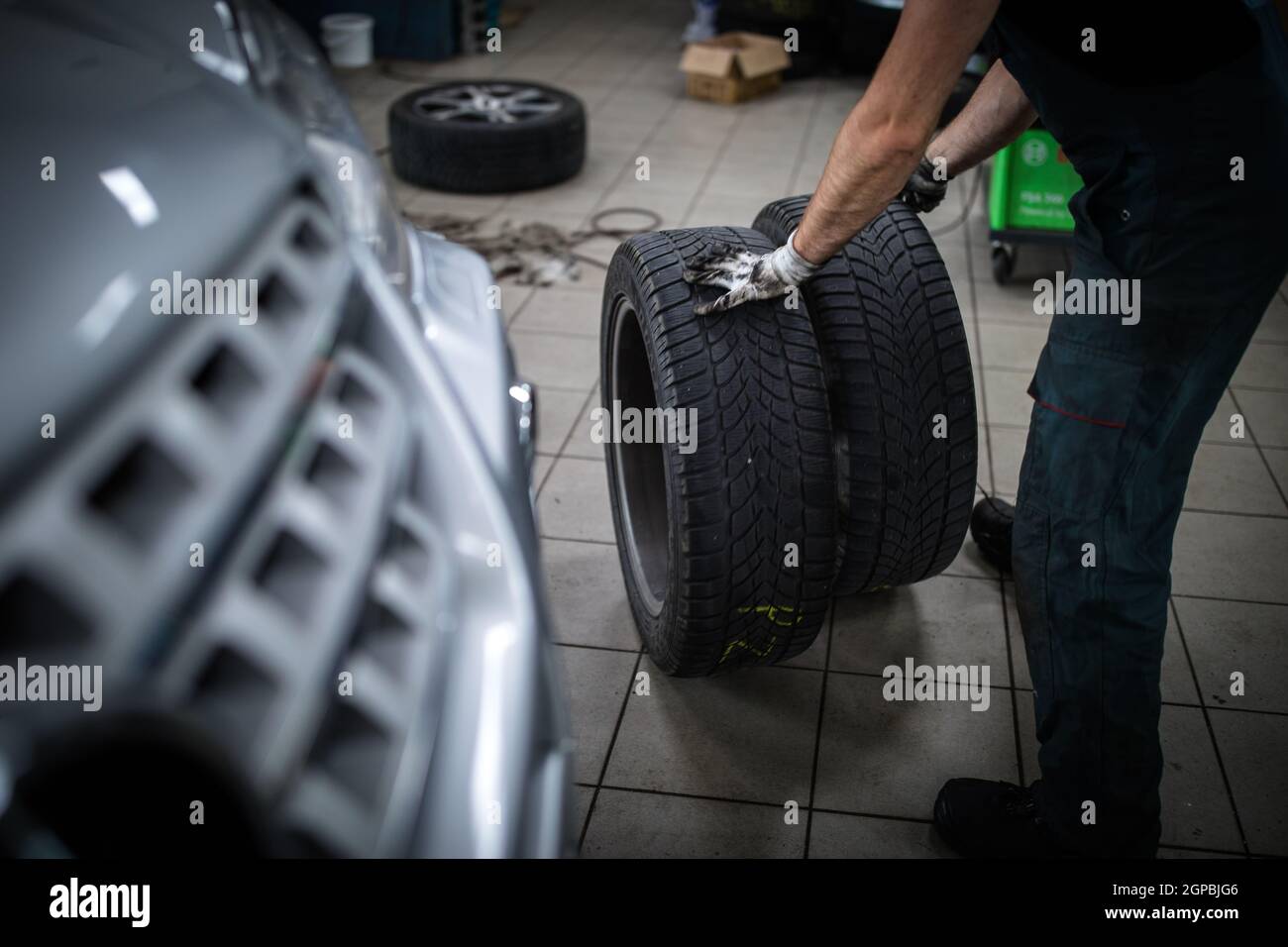 Car mechanic changind tires of a car in a repair shop/car garage ...