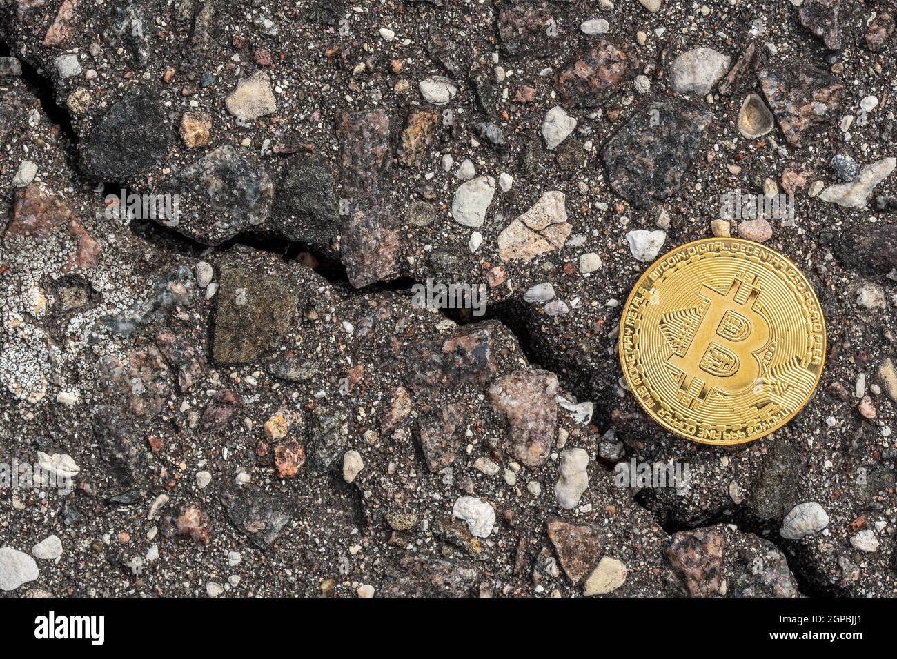 Shiny golden bitcoin on cracked pavement. Crack goes down as ...