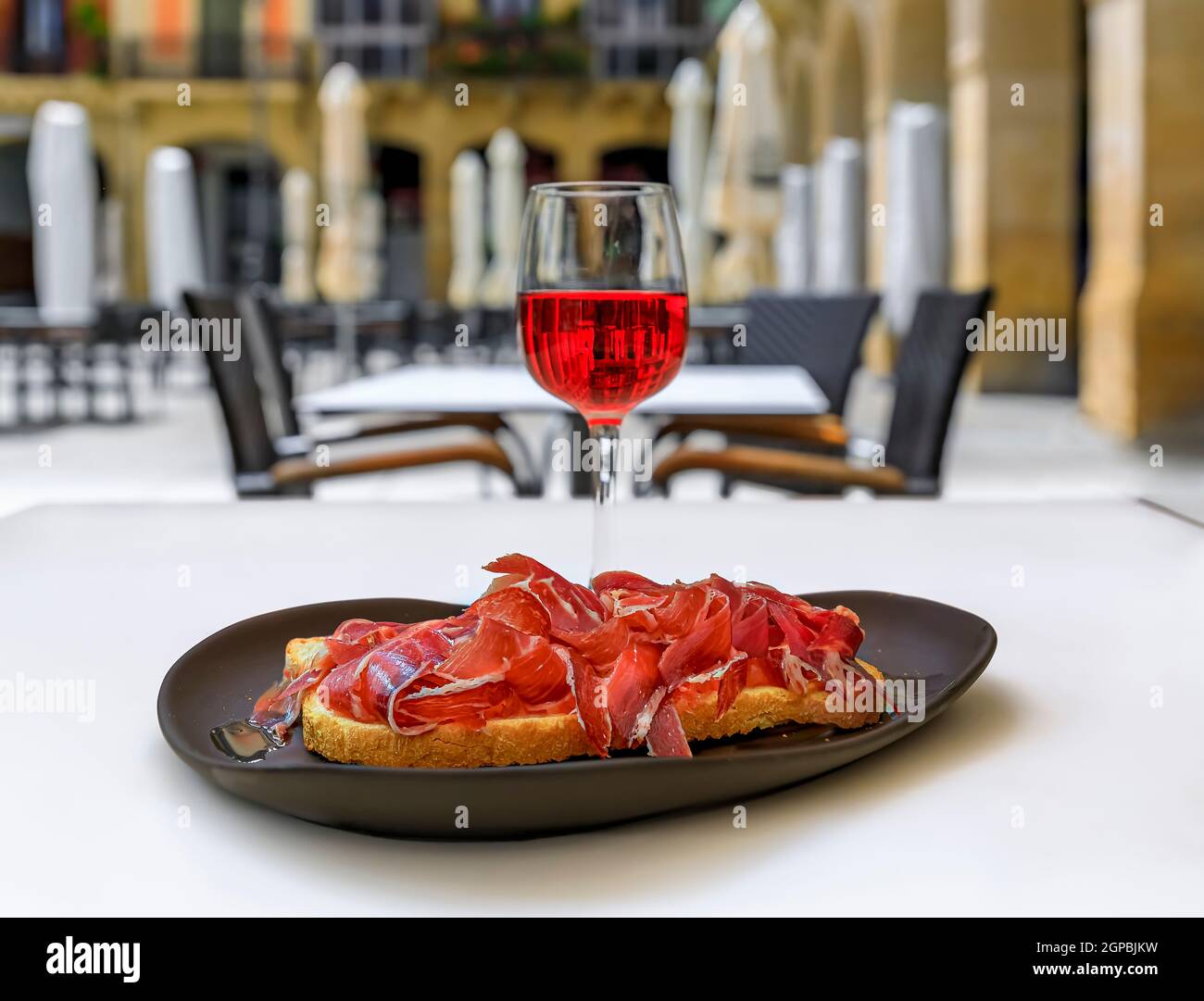 Glass of Spanish rose or rosado wine and Jamon Iberico tostada or ham ...