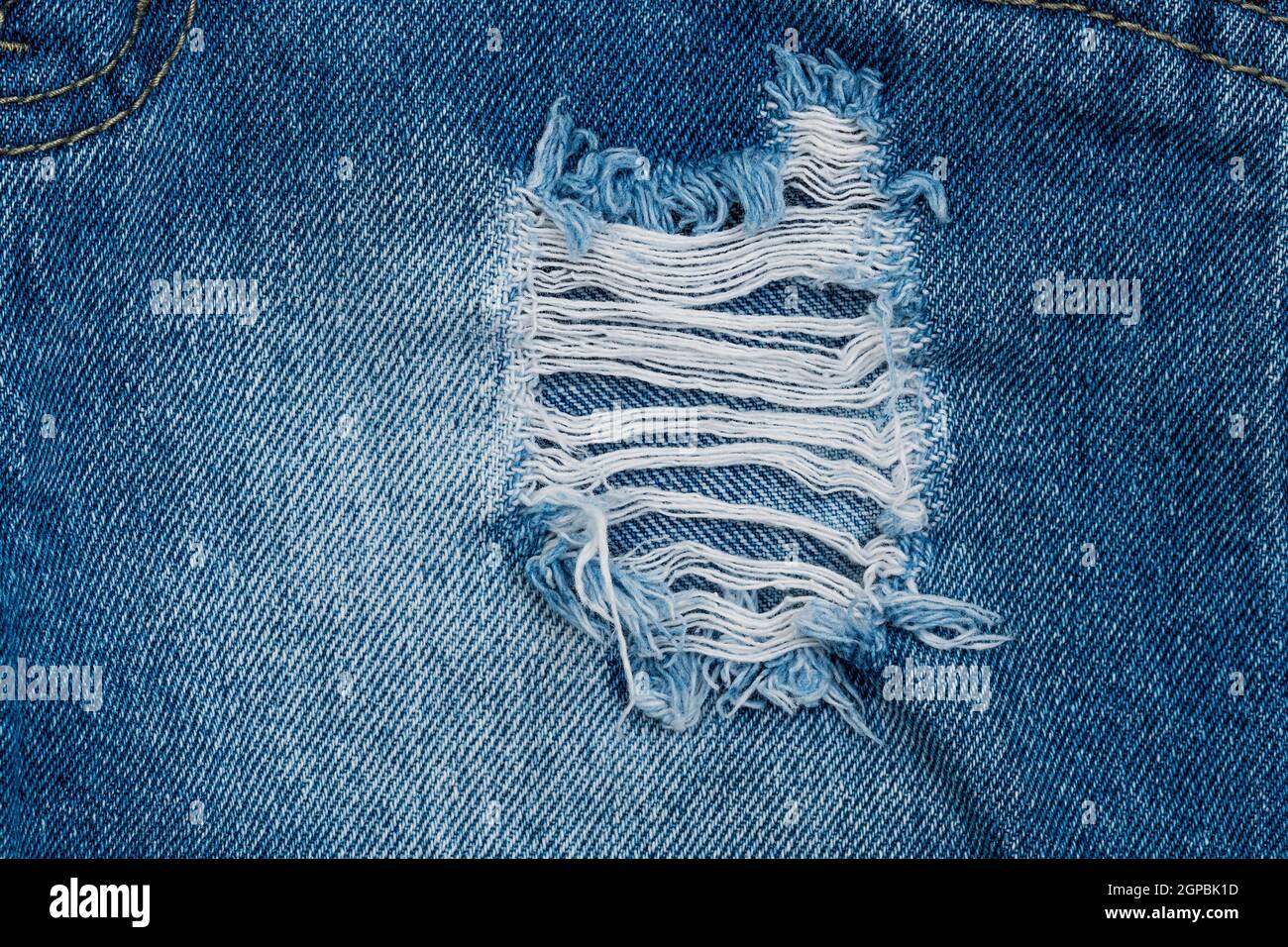 Hole and Threads on Denim Jeans. Close up blue jean texture Stock Photo ...