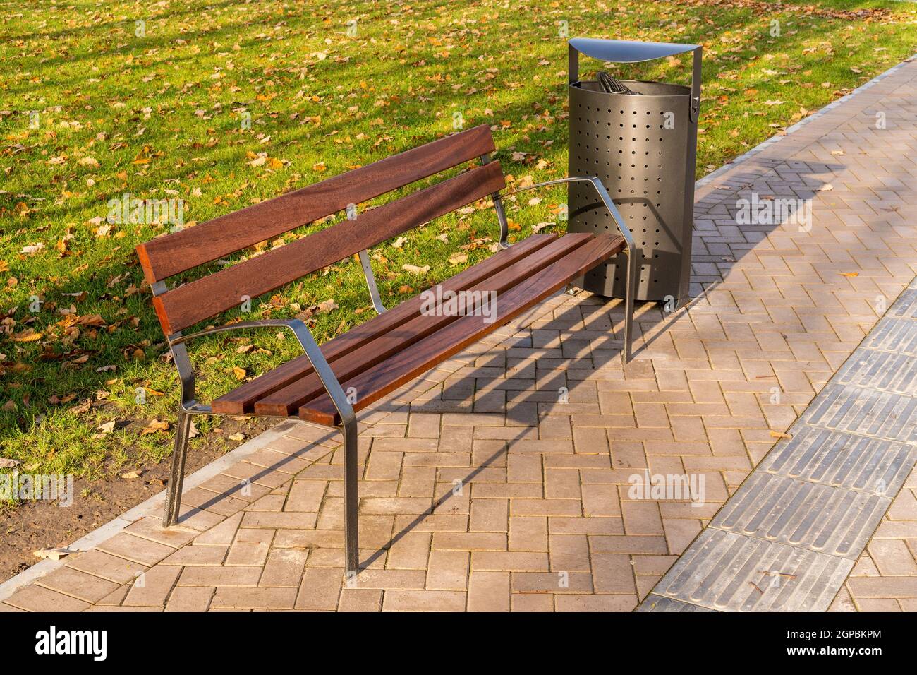 Wooden bench and trash can in the city park. Modern urban style of ...