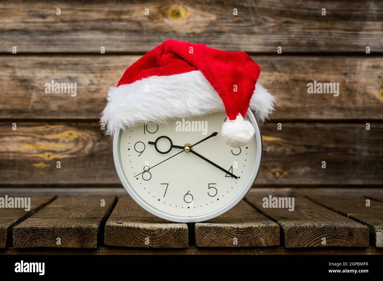 Christmas time - wall clock with Santa hat on the wheatered wood ...