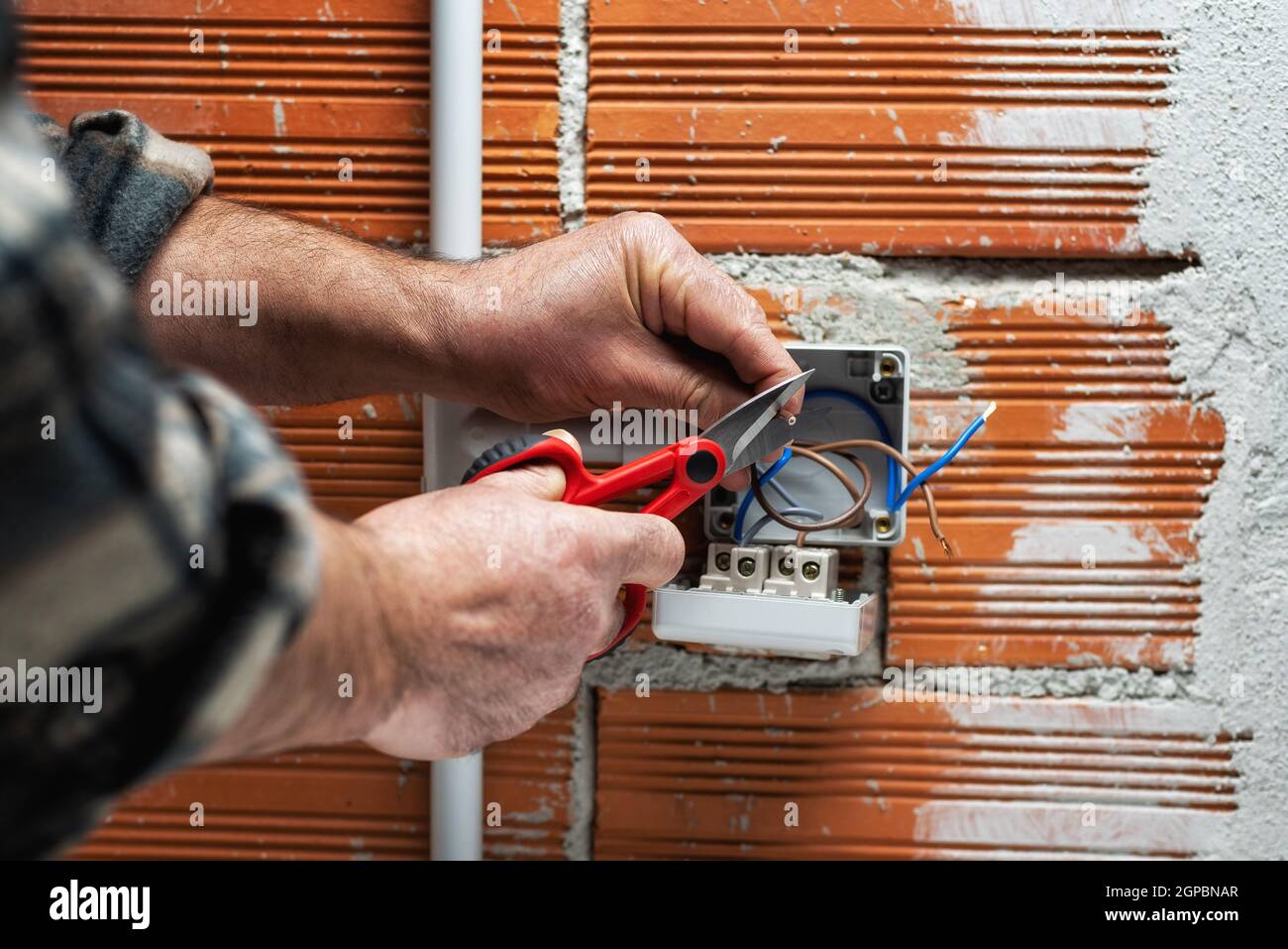 Electrician worker at work with scissors prepares electrical cables of ...