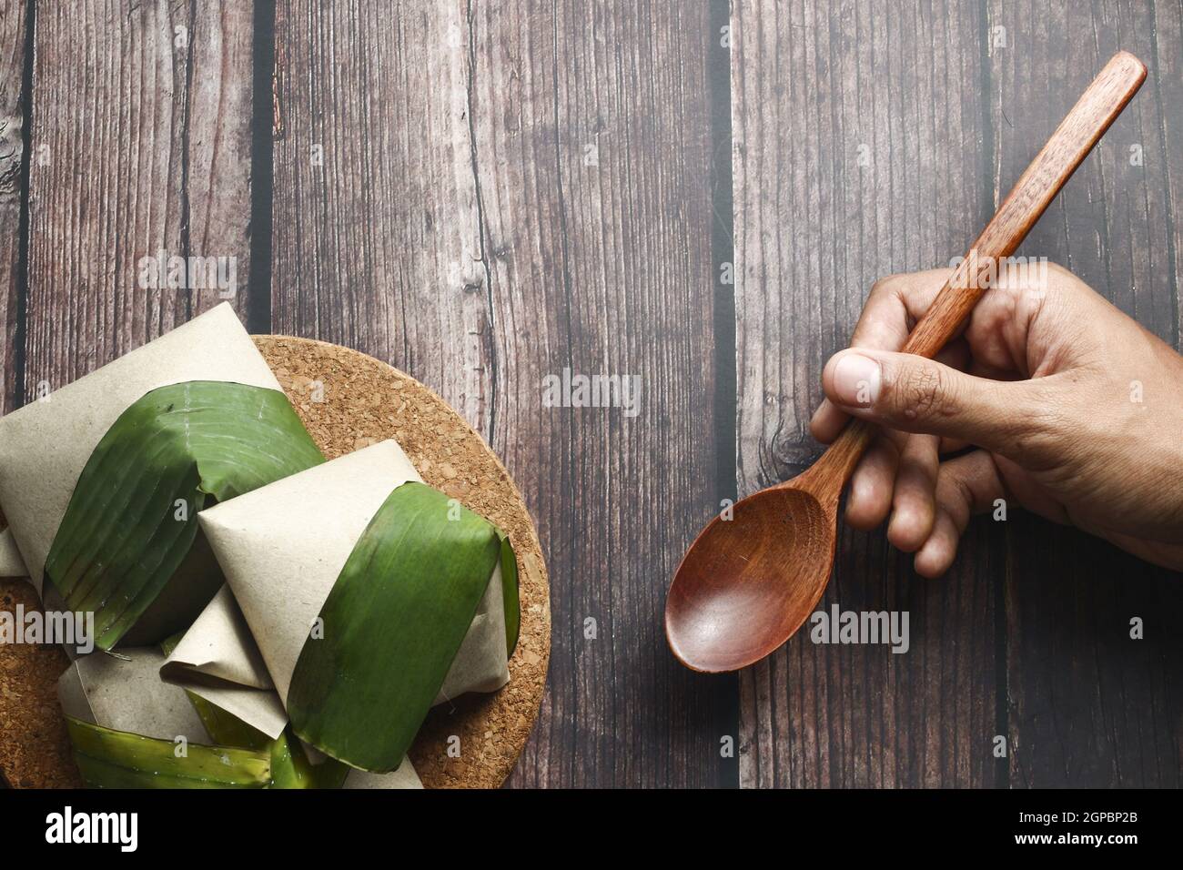 Top view of coconut flavored rice wrapped in banana leaves and a hand ...