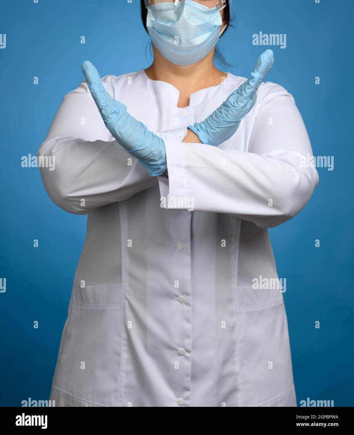 female medic in a white coat, a mask stands on a blue background, arms ...