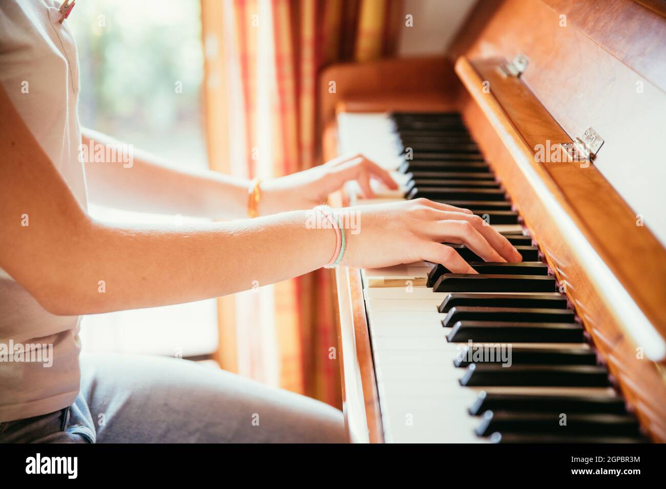 Young girl is practicing piano at home. Clipping of piano and hands ...