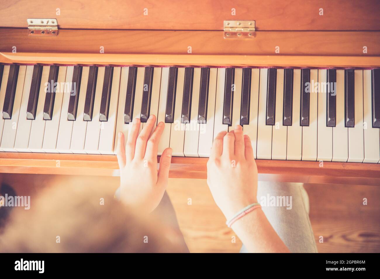 Young girl is practicing piano at home. Clipping of piano and hands ...