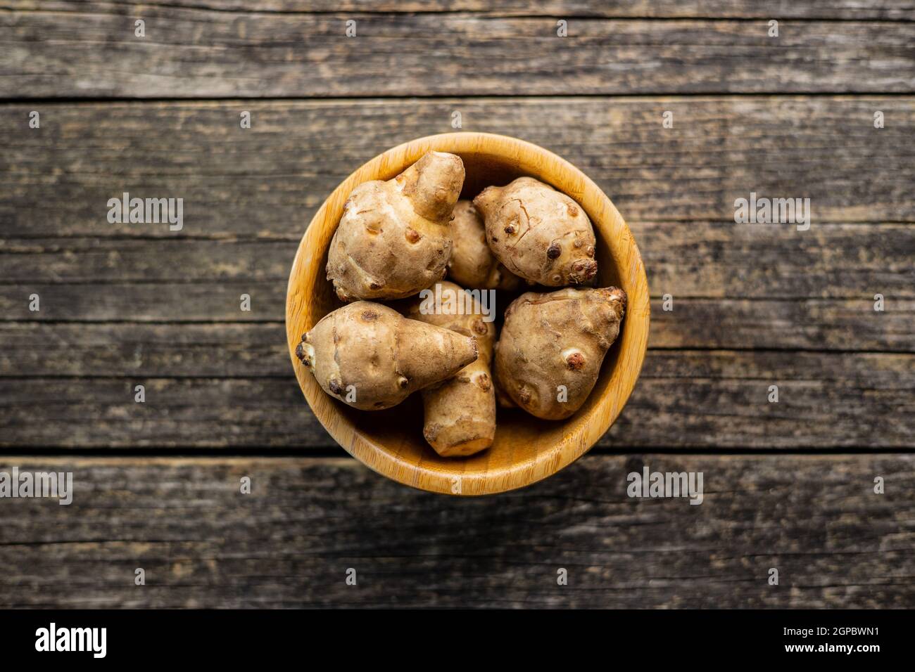 Raw jerusalem artichoke. Topinambur vegetable root in wooden bowl. Top ...