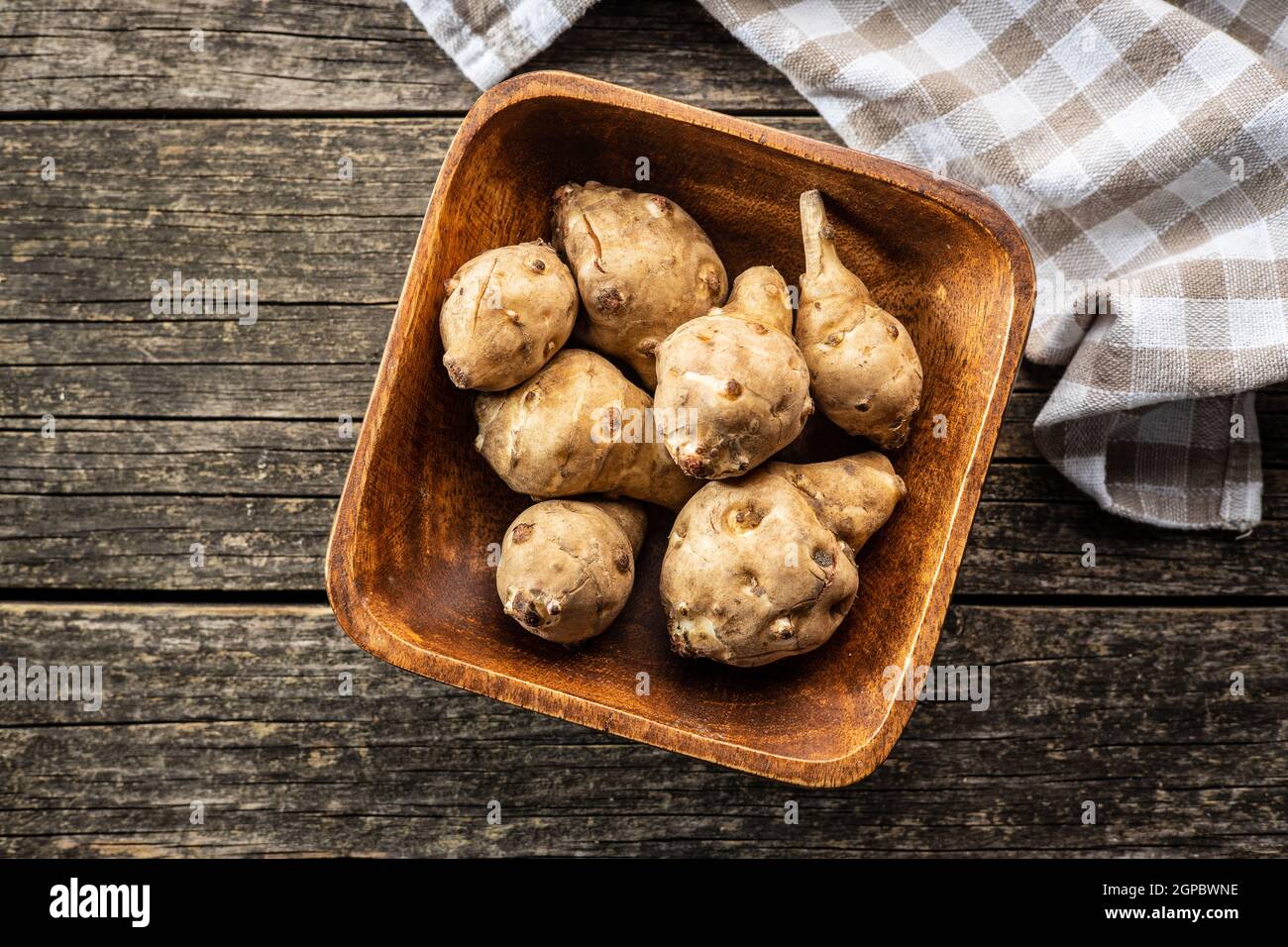 Raw jerusalem artichoke. Topinambur vegetable root in wooden bowl. Top ...