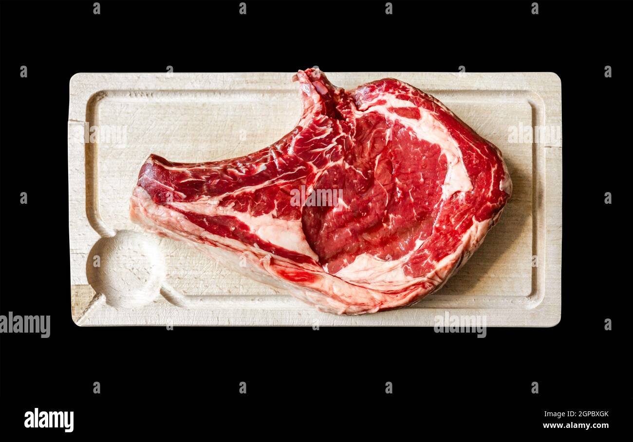 Raw beef prime rib on a cutting board isolated on black background. Top ...