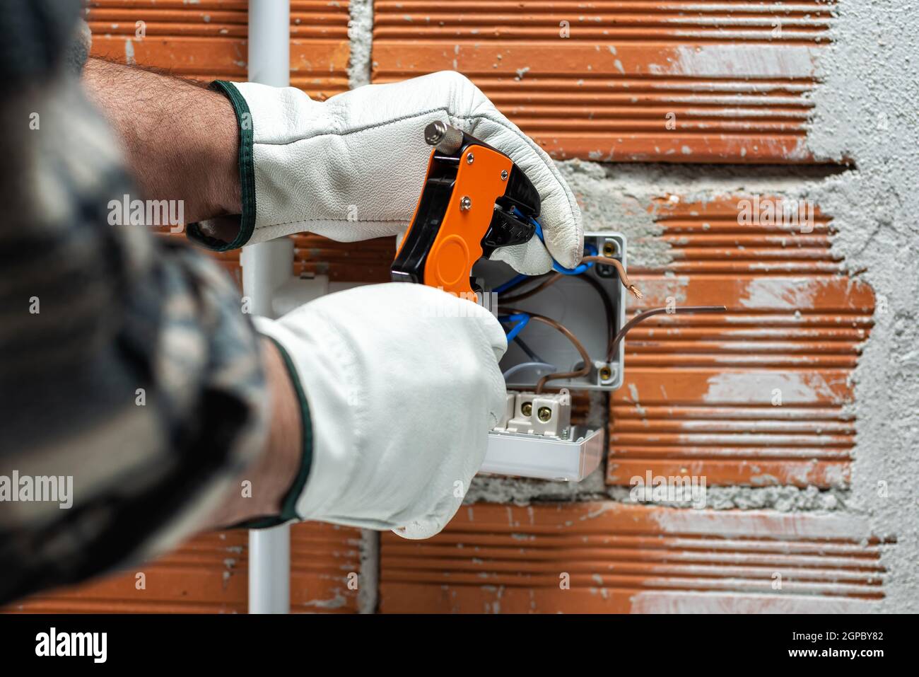 Electrician worker at work with wire stripper prepares electrical ...