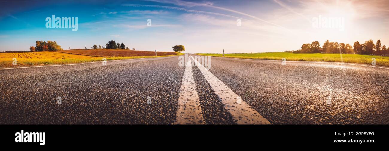 Wide asphalt road panorama in countryside in sunset on summer. Route ...