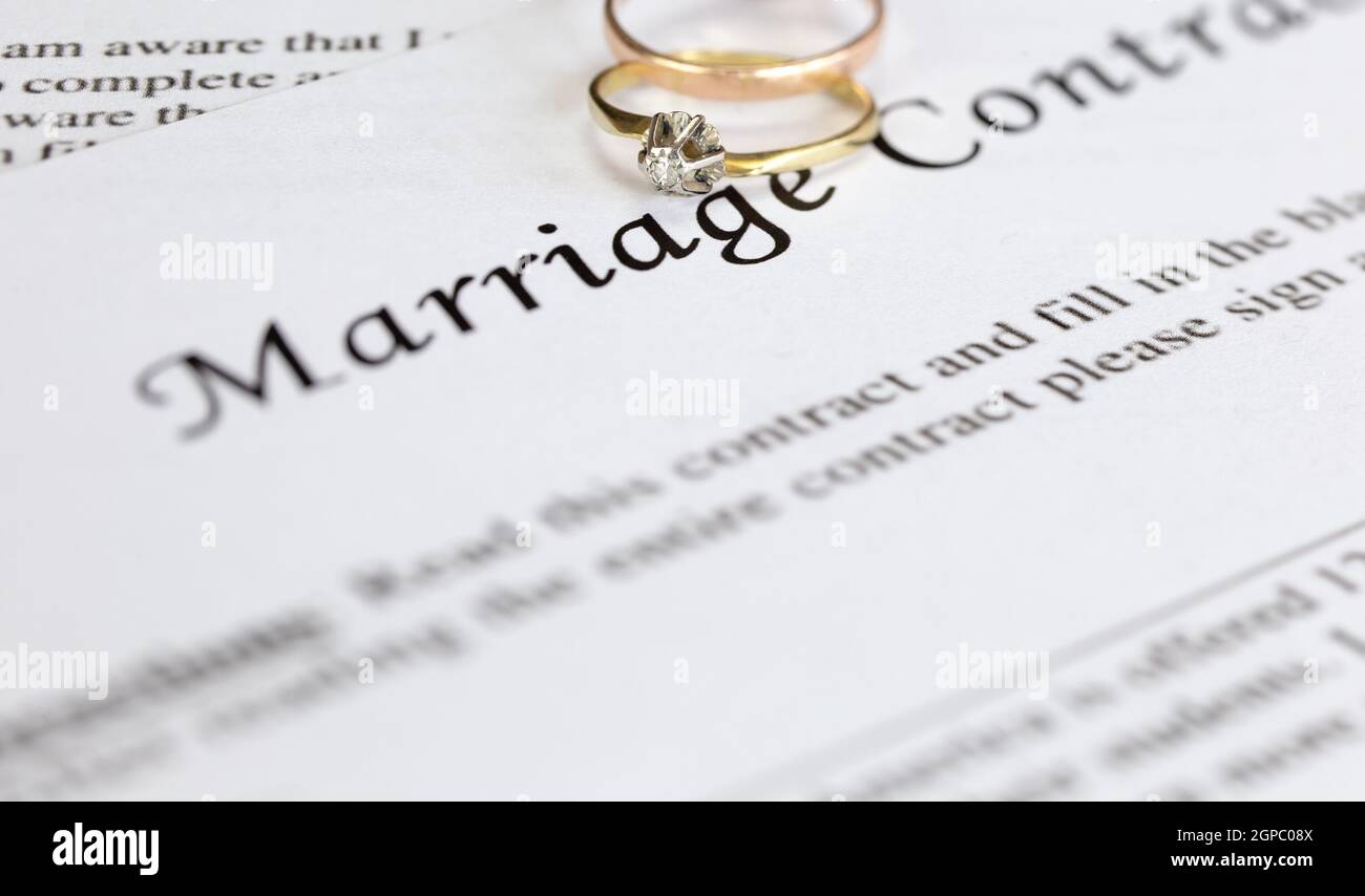 Marriage contract with two golden wedding rings and gold pen ...