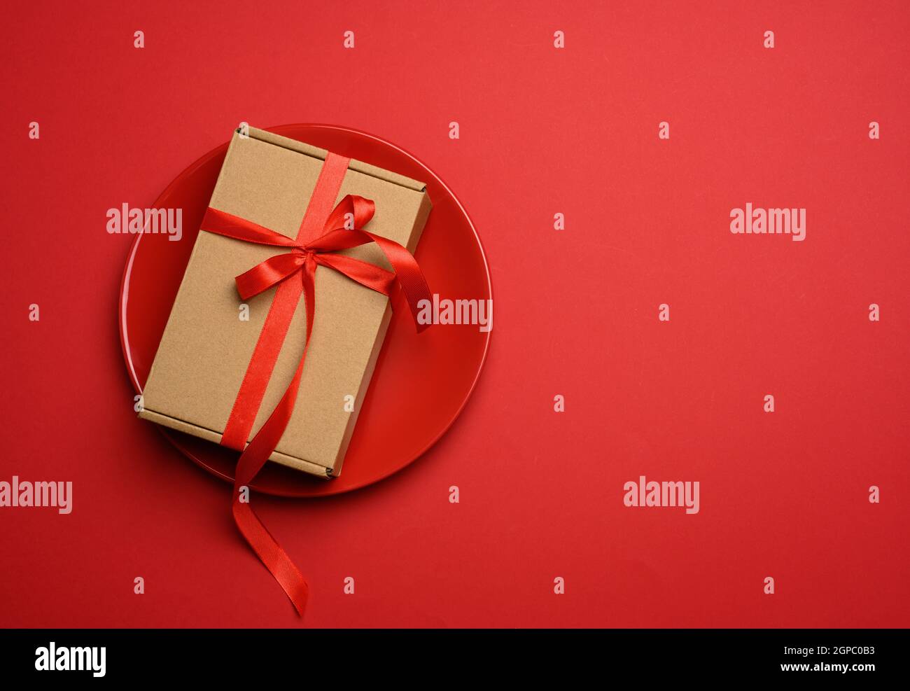 rectangular brown cardboard box tied with a silk red ribbon lies in a ...