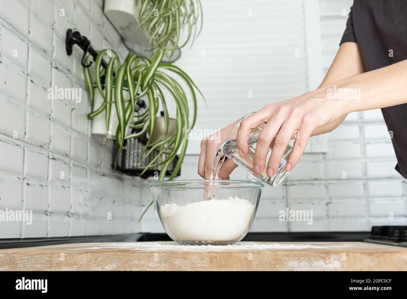 Pouring Water into Flour. Making dough by female hands in white moden ...