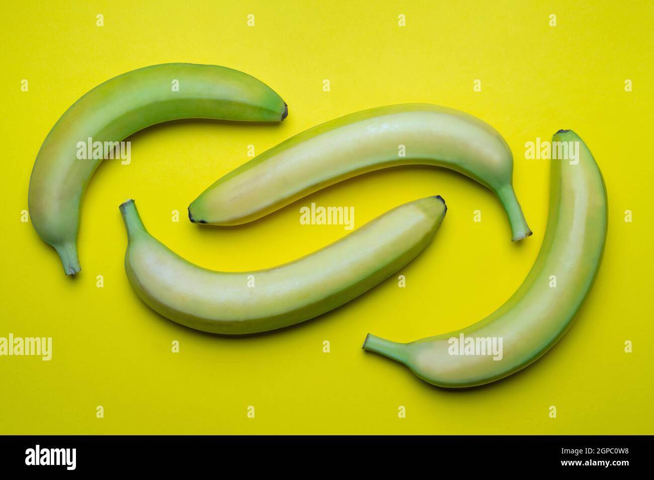 Four bananas on a yellow surface Stock Photo - Alamy