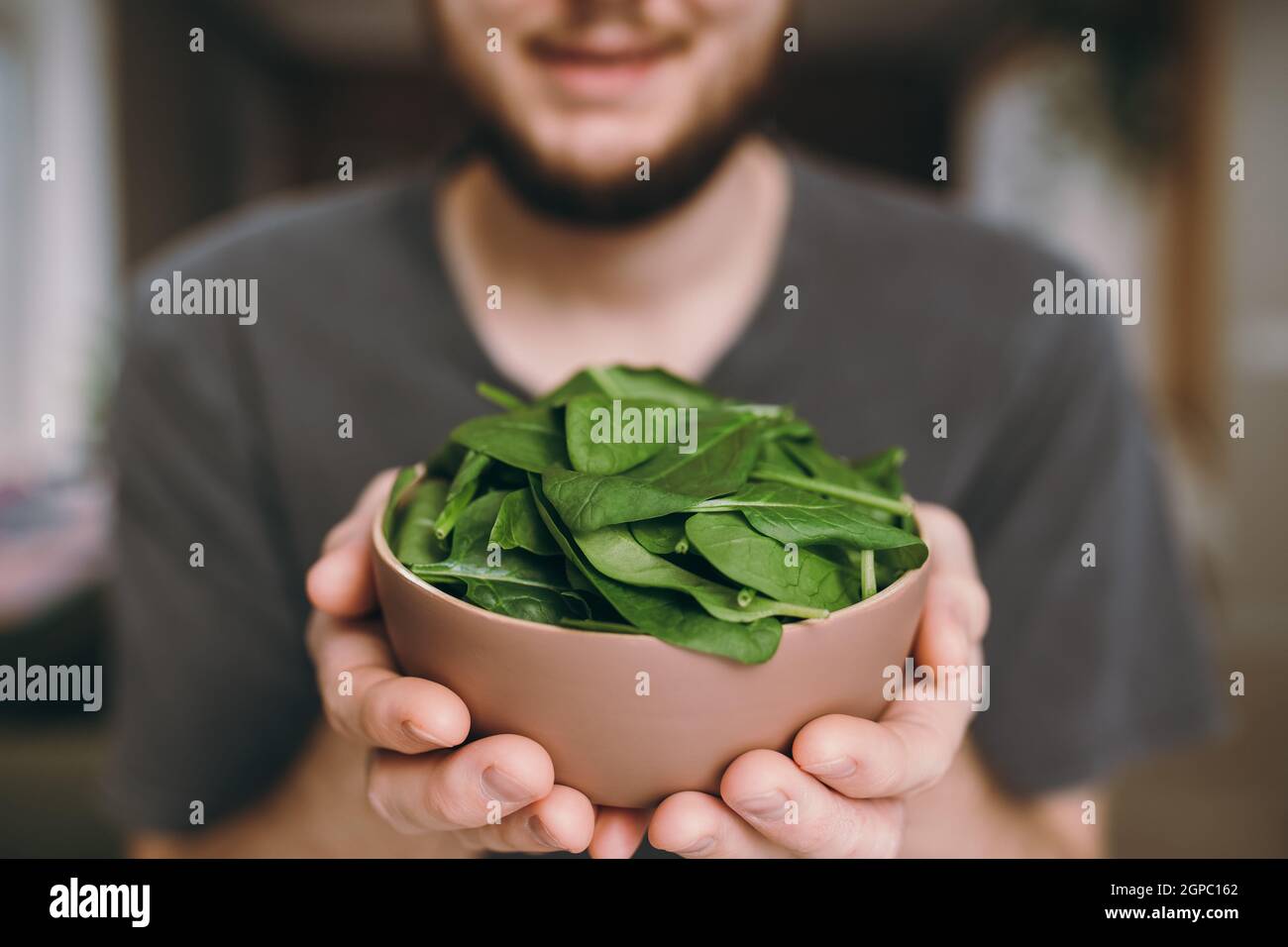 Hands of man holding fresh green salad leaves of spinach on blurred ...