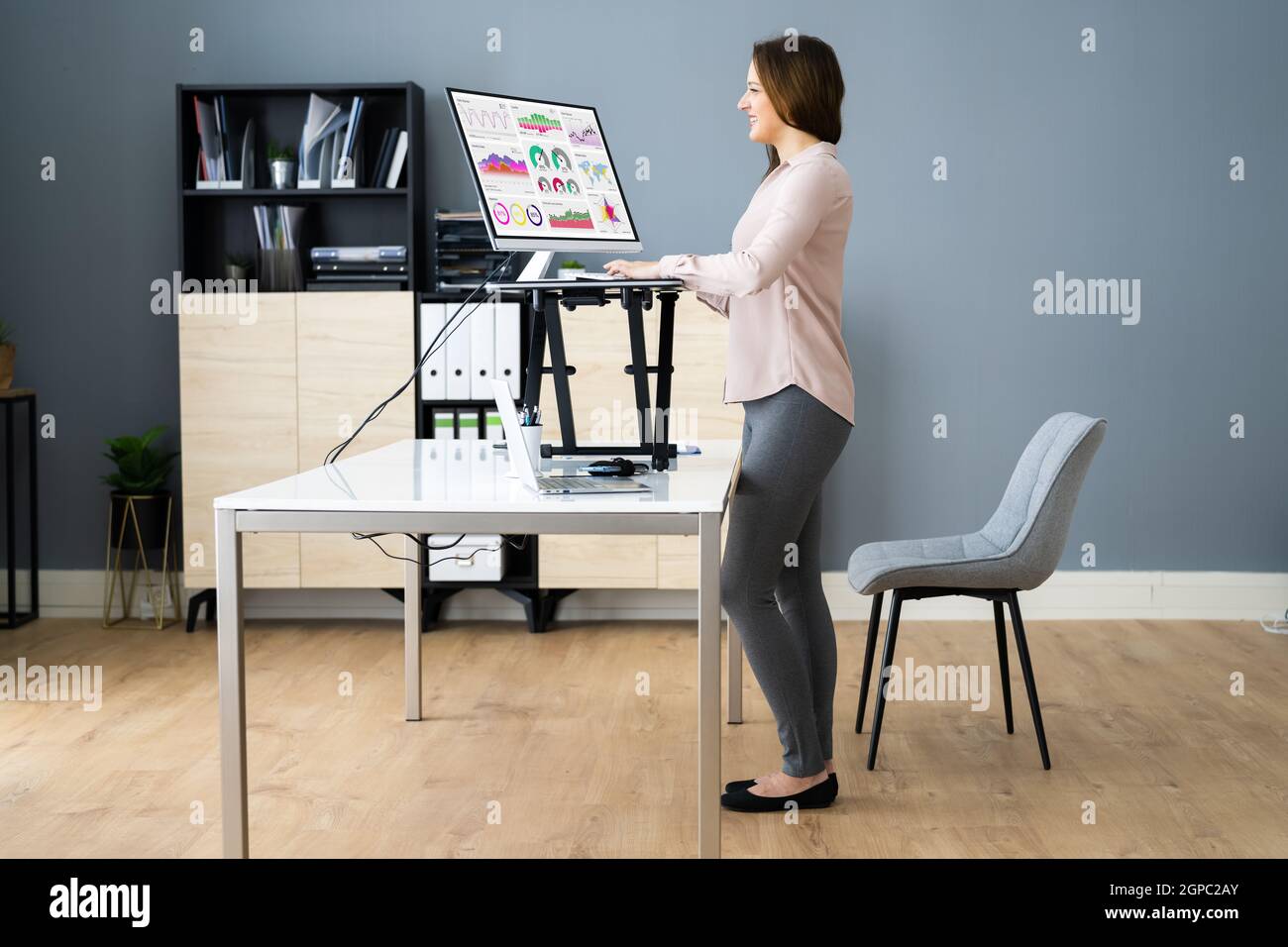 Adjustable Height Desk Stand In Office Using Computer Stock Photo - Alamy