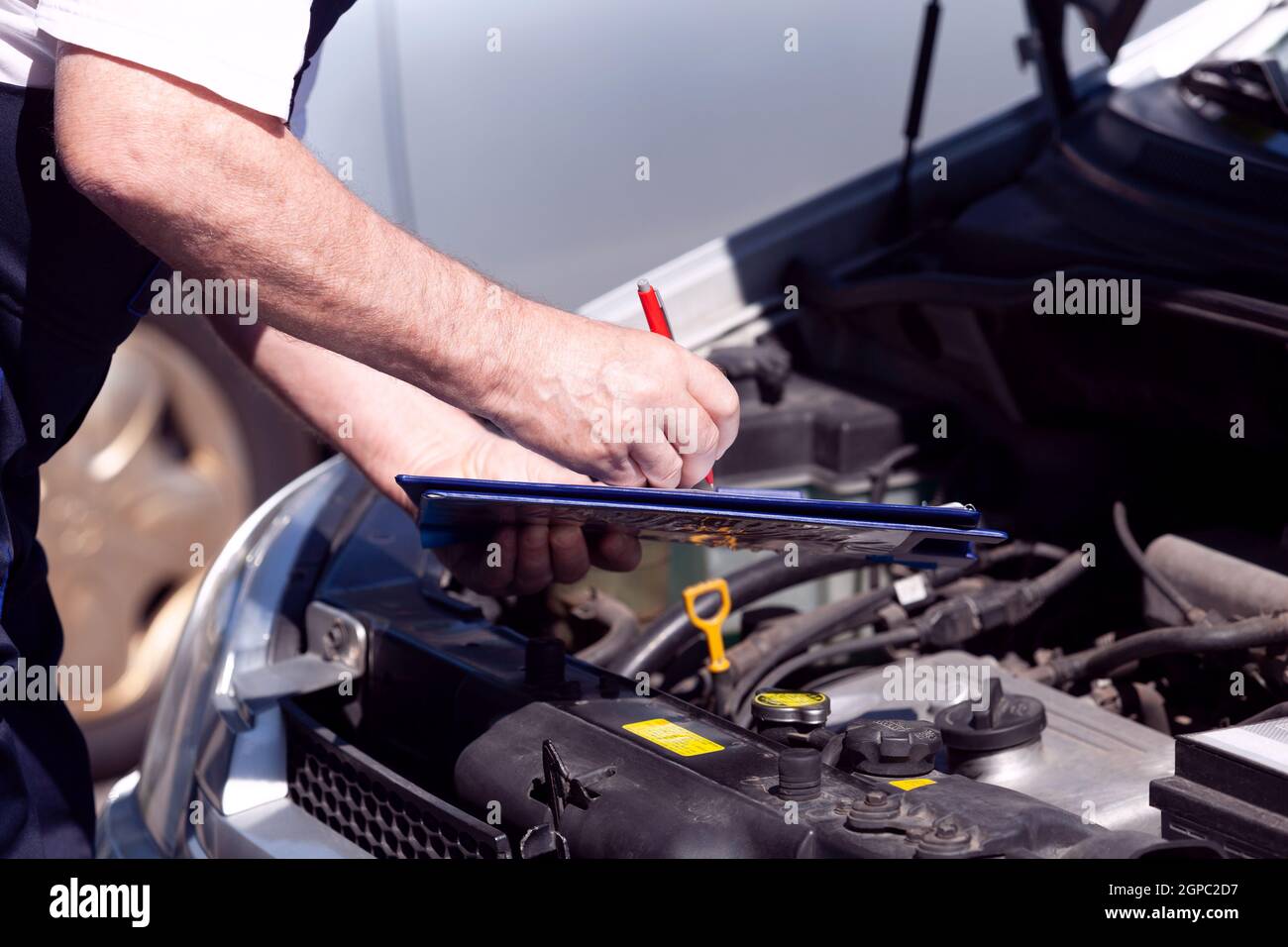 Auto mechanic checking car engine and writing on the clipboard Stock ...