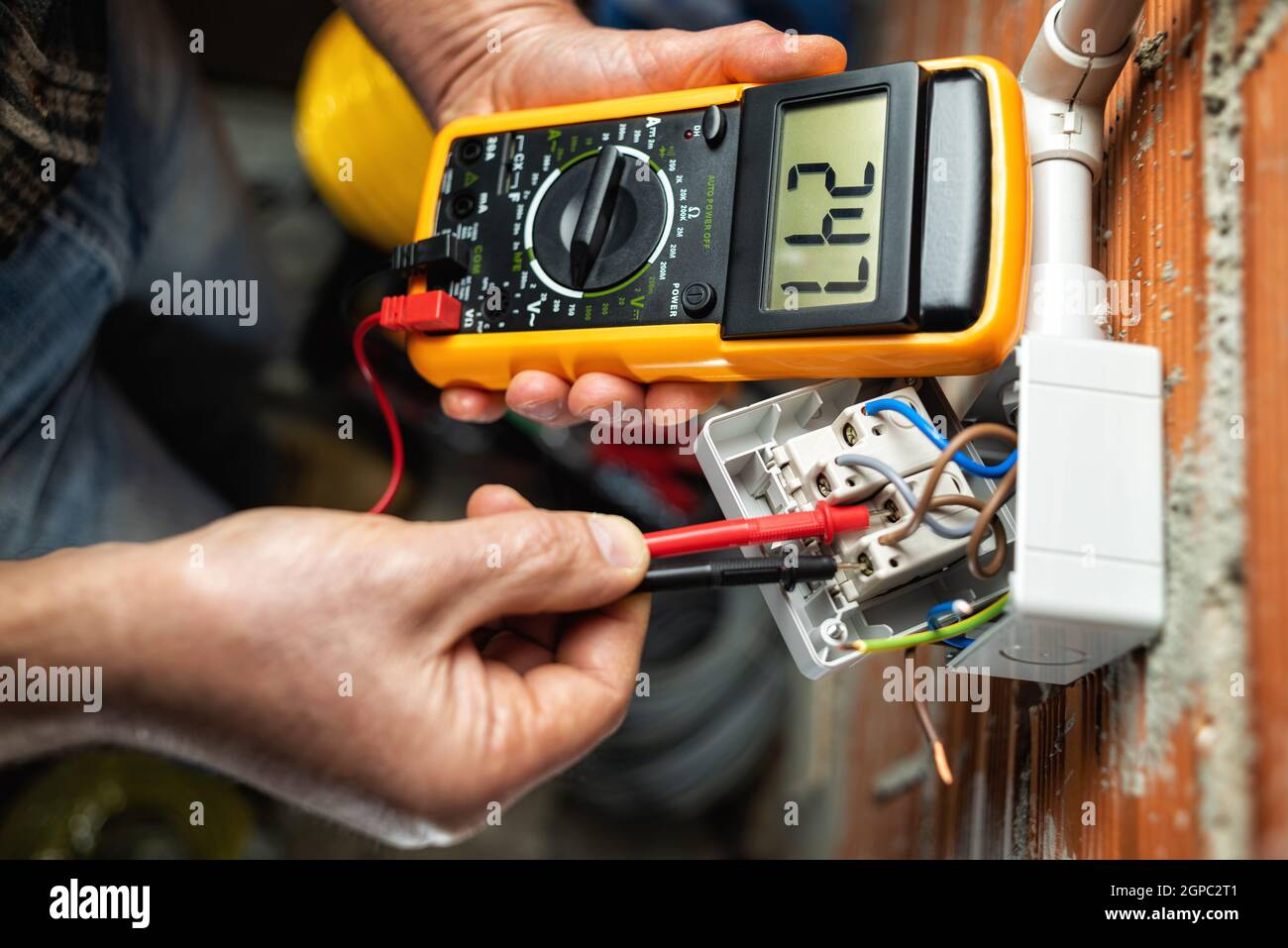 View from above. Electrician worker at work with the tester measures ...