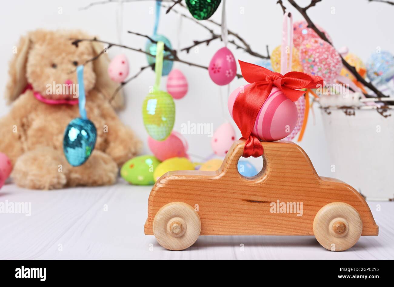 wooden toy car carrying a pink Easter egg fixed with a red ribbon ...