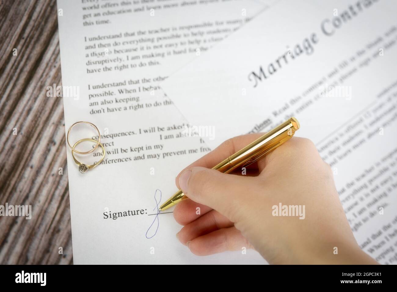 Marriage contract with two golden wedding rings and gold pen ...