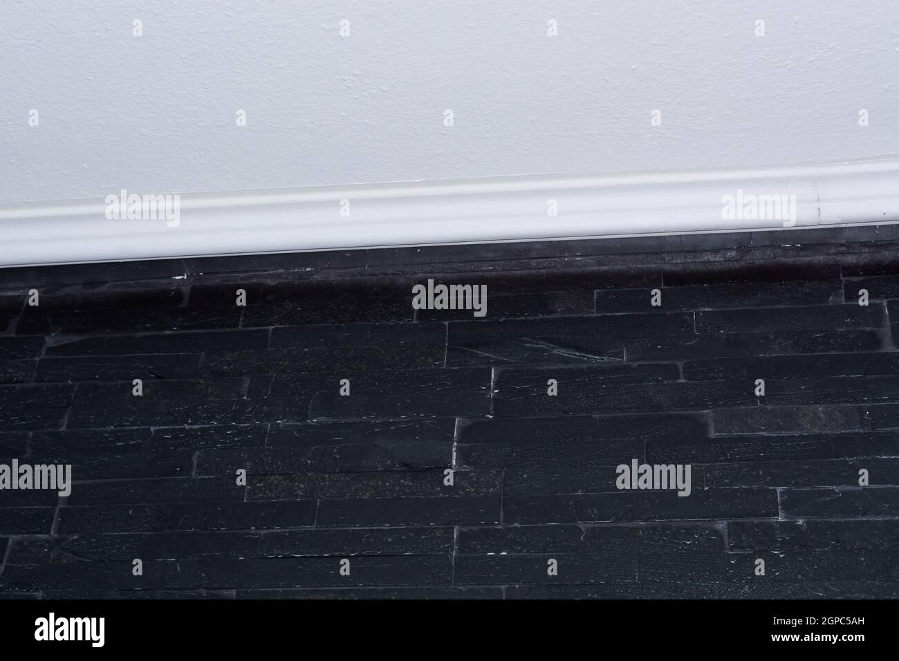 Wall with black bricks or straps tiles Stock Photo - Alamy