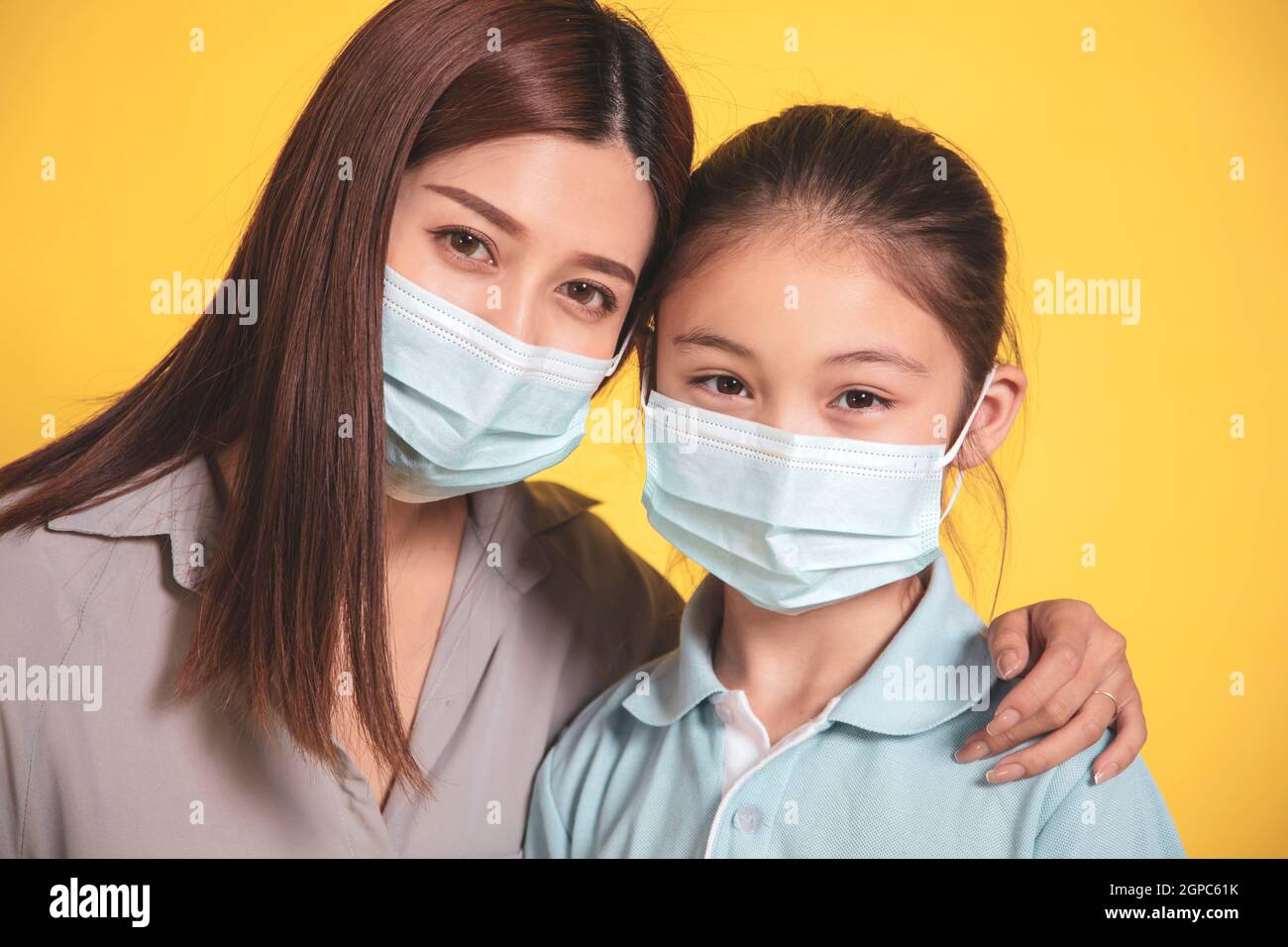 mother hugs little daughter in protective medical masks during Covid-19 ...