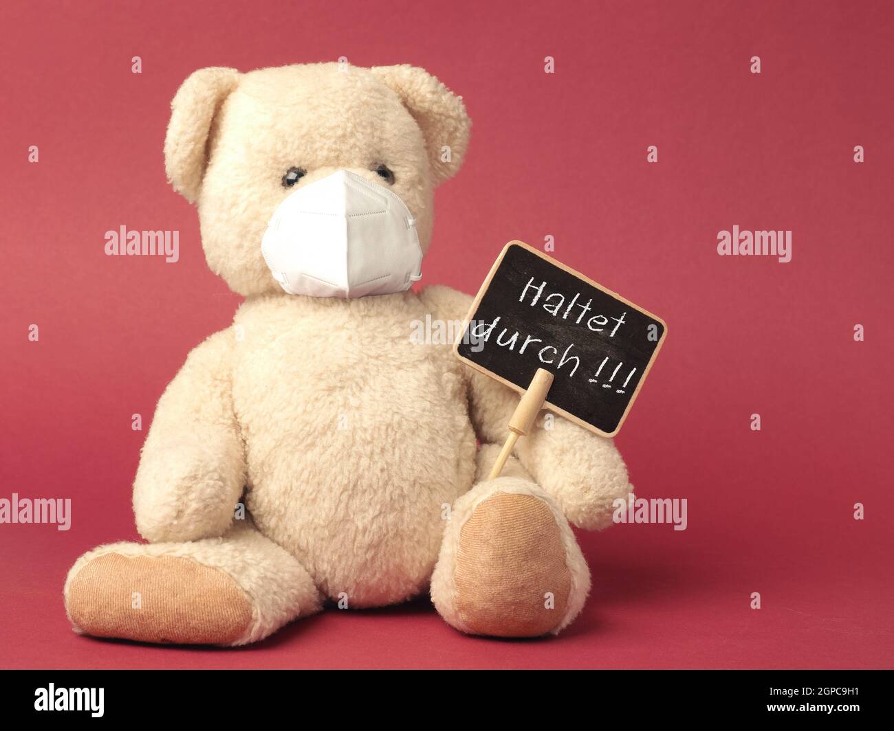 Teddy bear with protective mask holds sign with the German inscription ...